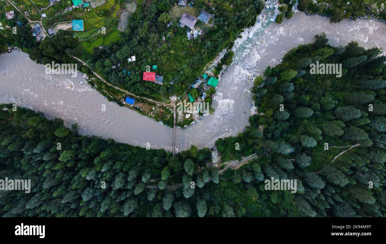 An aerial top view of a river flowing through green forests and rural houses on fields Stock ...