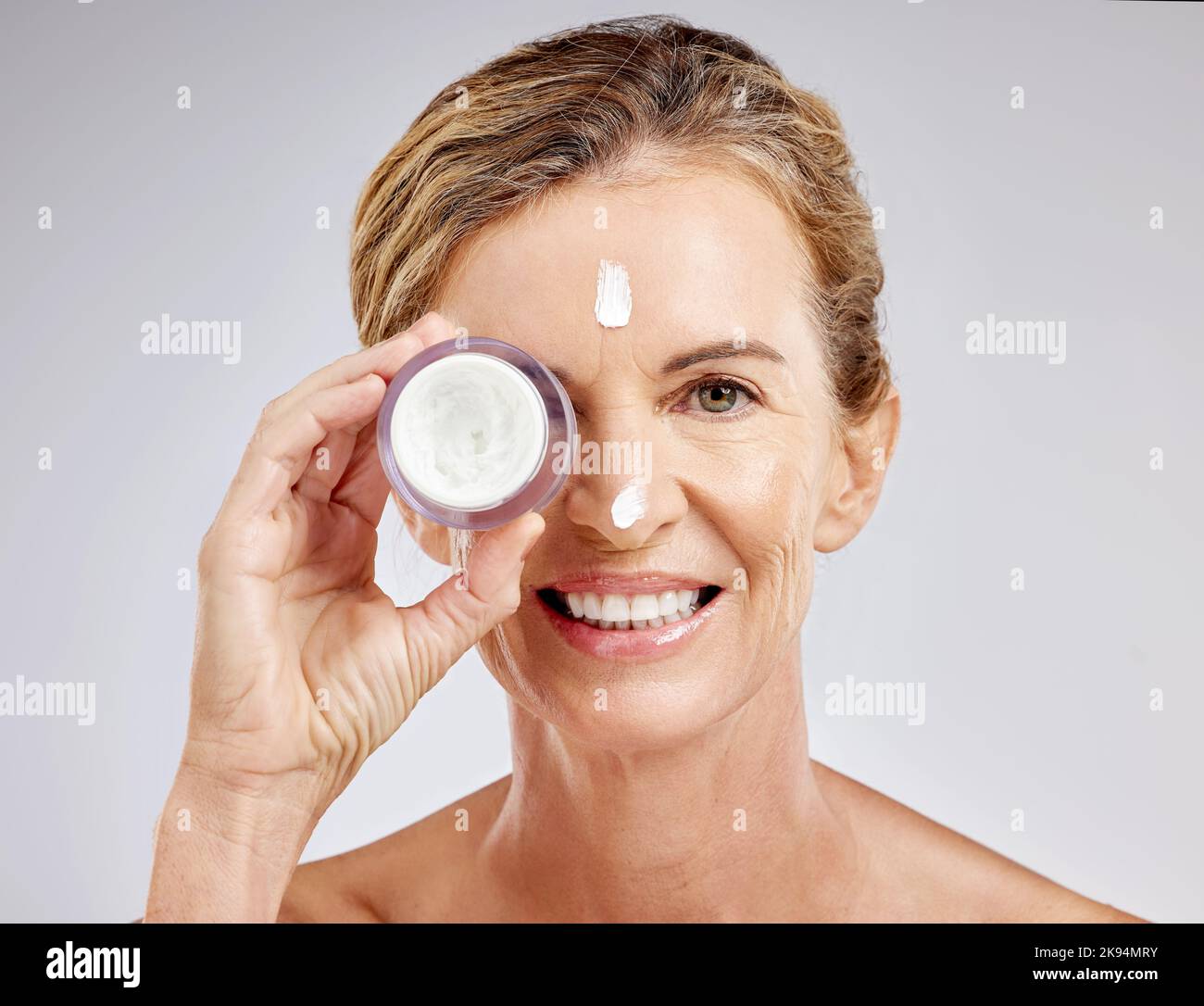Skincare, beauty and cream on face of mature woman with a smile for ...