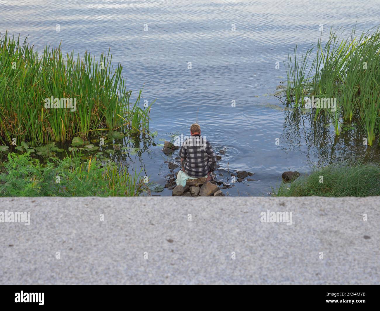An old man in shorts and a cap and a fishing rode in his hands pulling ...