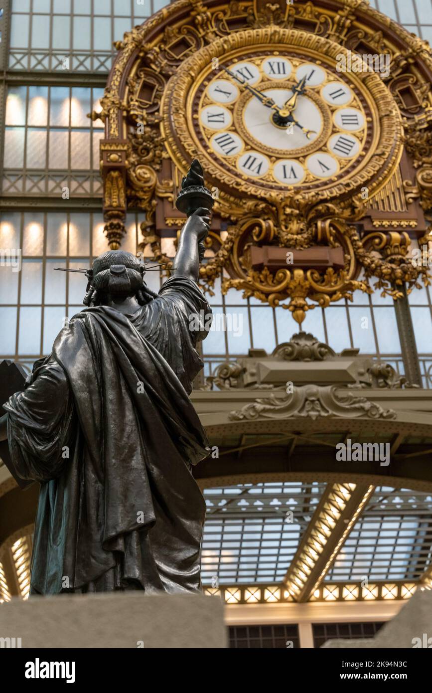 A statue points towards large golden clock Stock Photo - Alamy