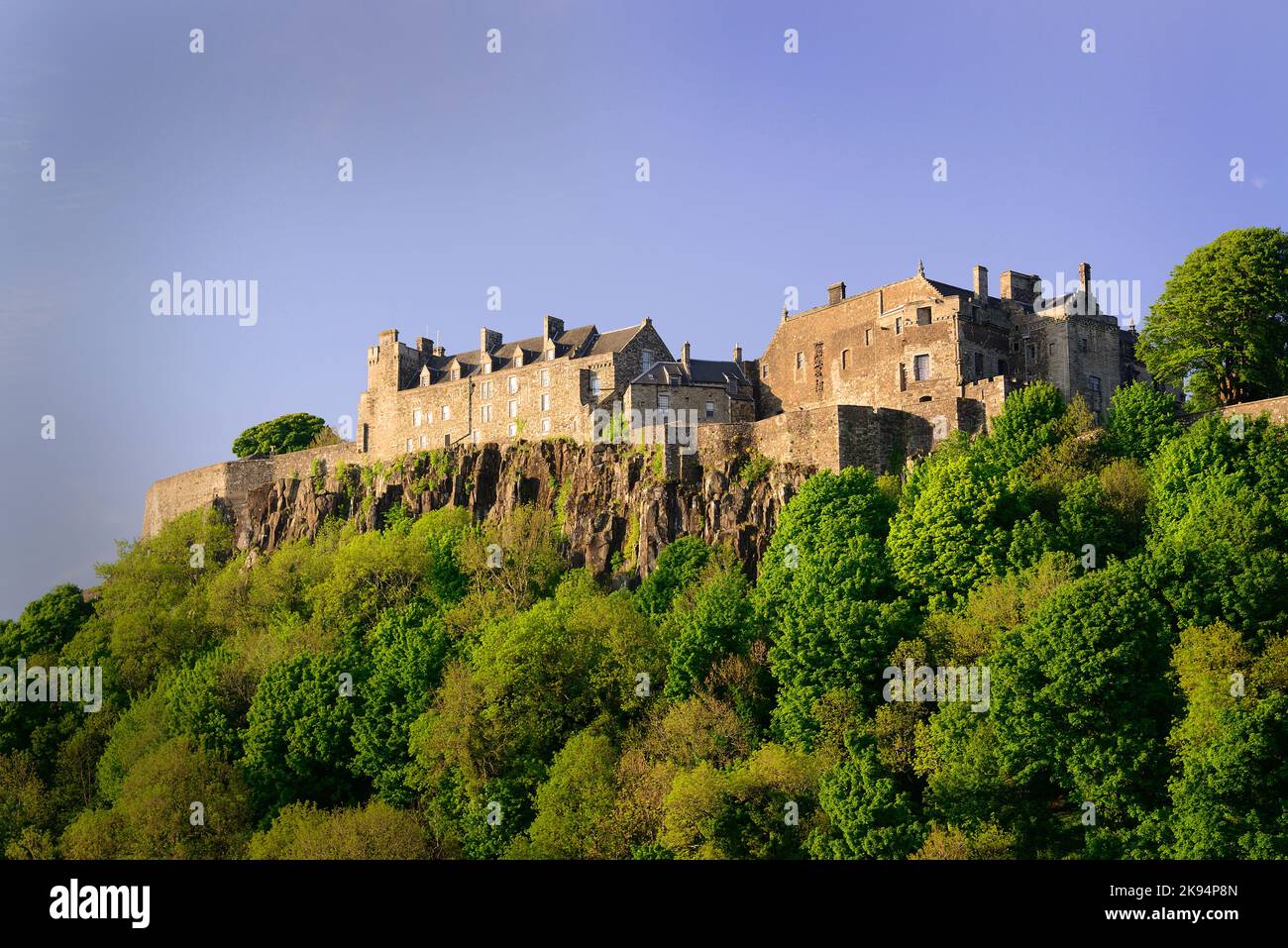 The low-angle view of Stirling Castle on top of the green cliff under ...
