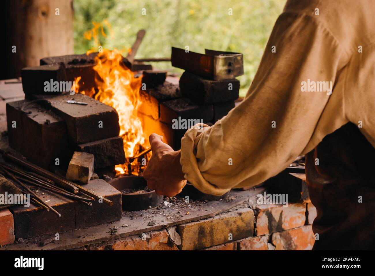 A blacksmith hardens steel at high temperature in a homemade furnace in ...