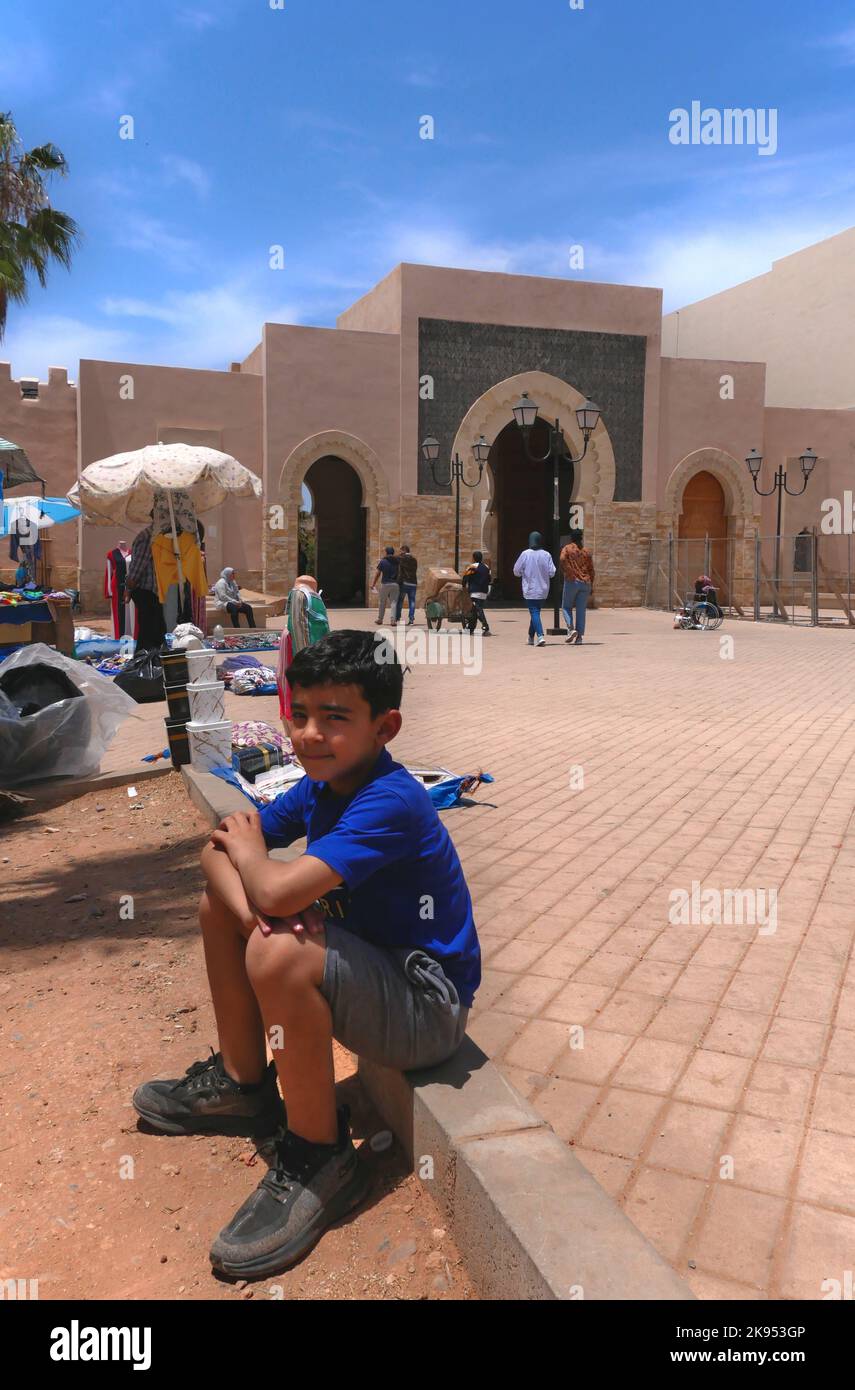 A vertical closeup of a young boy sitting on the curb. Agadir, Morocco ...