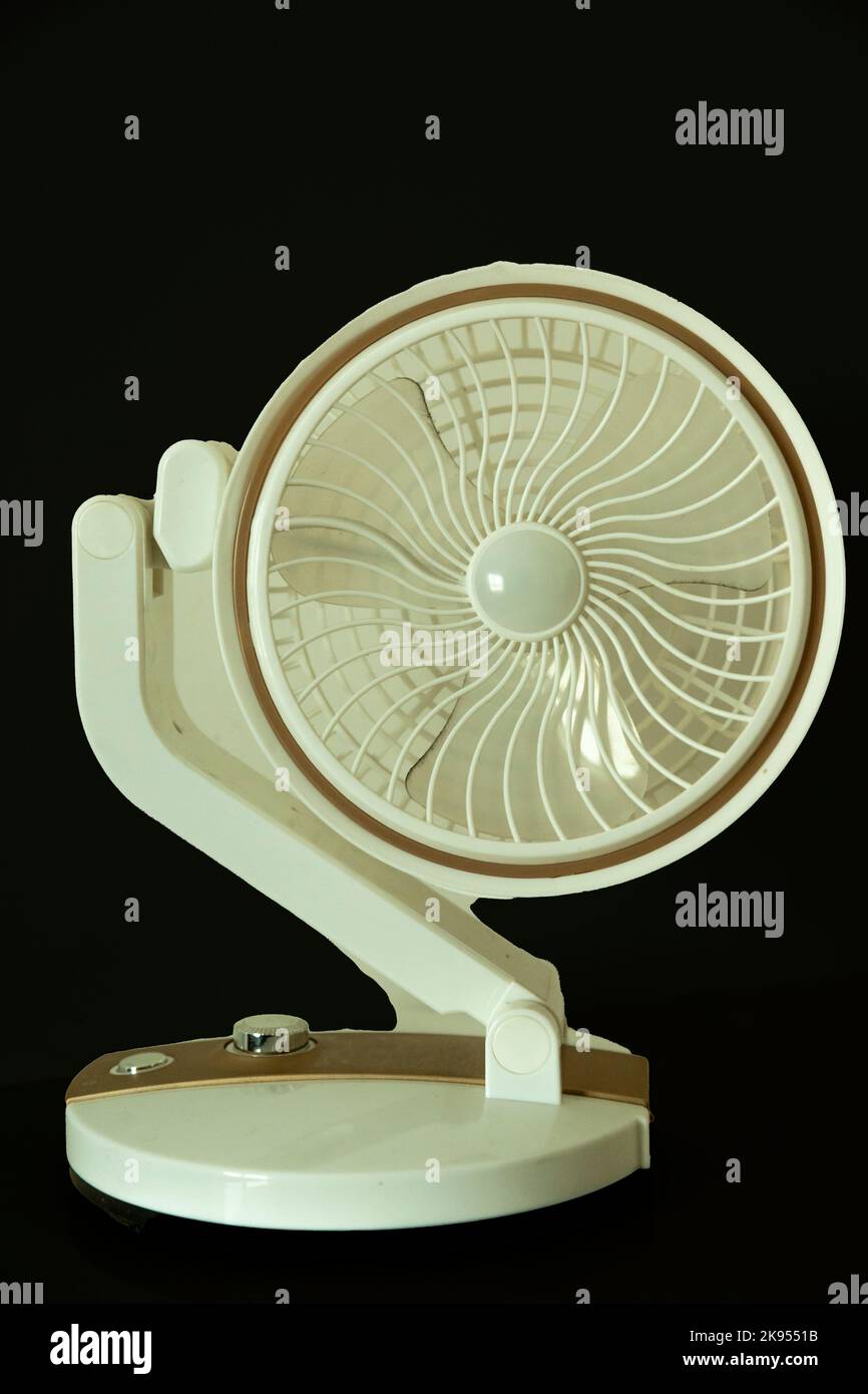 White table fan on a table with black background Stock Photo - Alamy