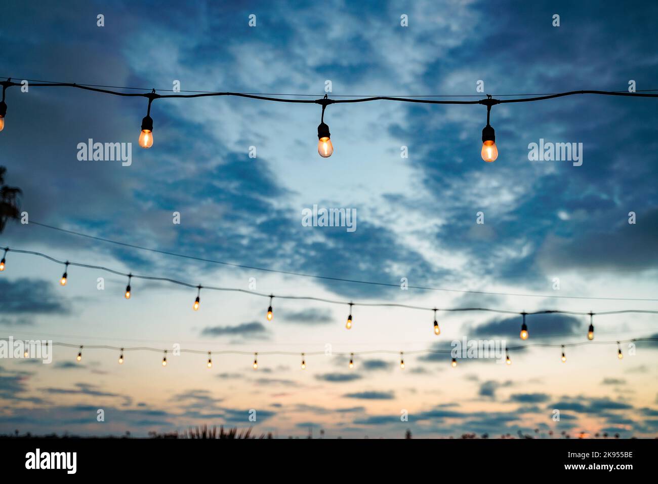 outdoor string lights in beautiful blue and orange sunset sky. Chill ...