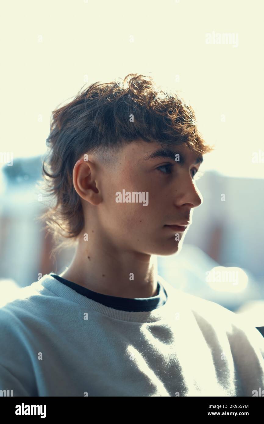 A vertical portrait of a young Caucasian boy with a fresh mullet ...