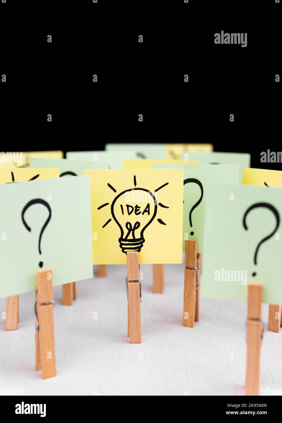 Light bulb doodle drawn on sticky note among many question marks. Hand ...