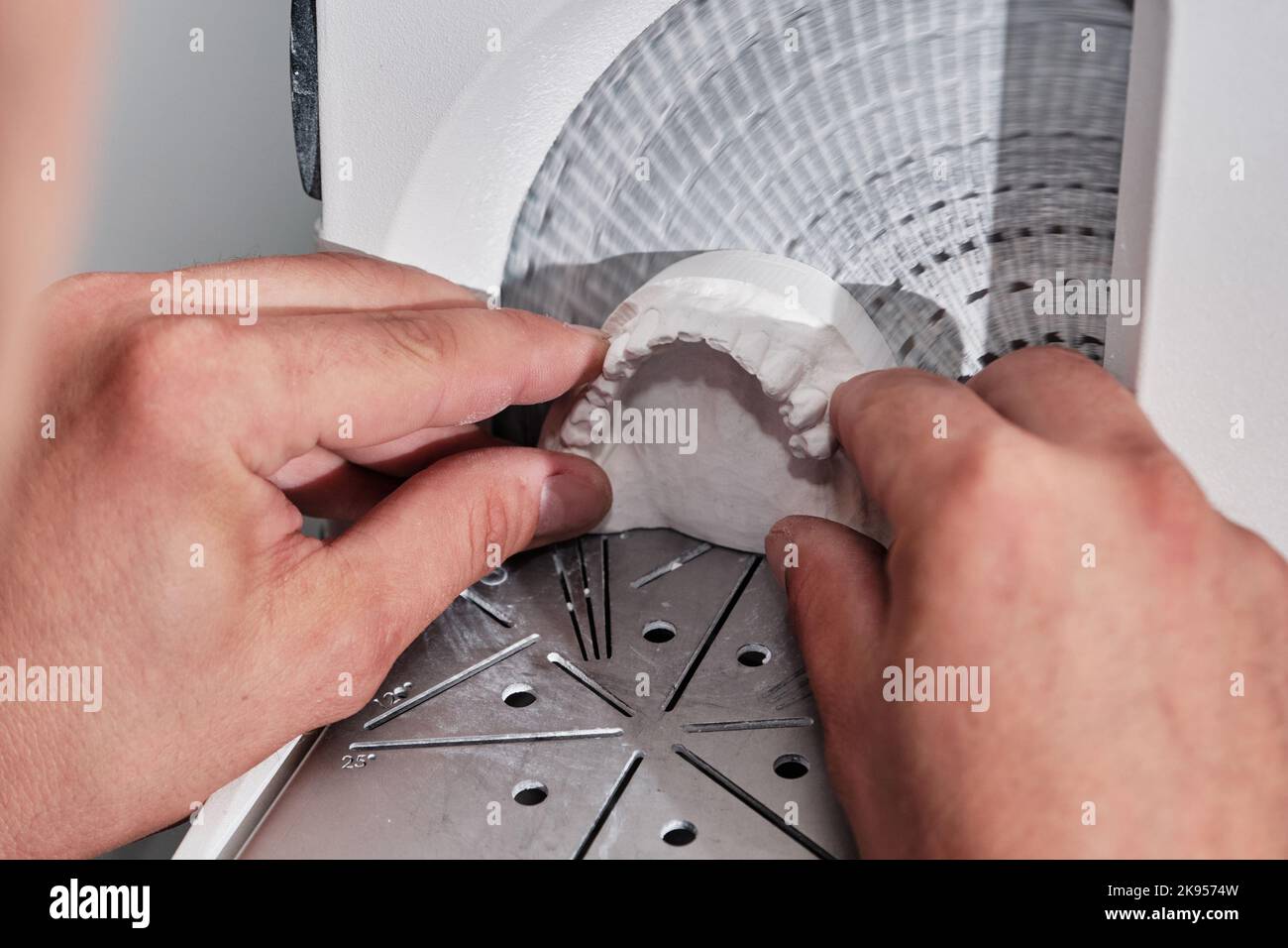 Dental technician trimming excess material from plaster models. Dental ...