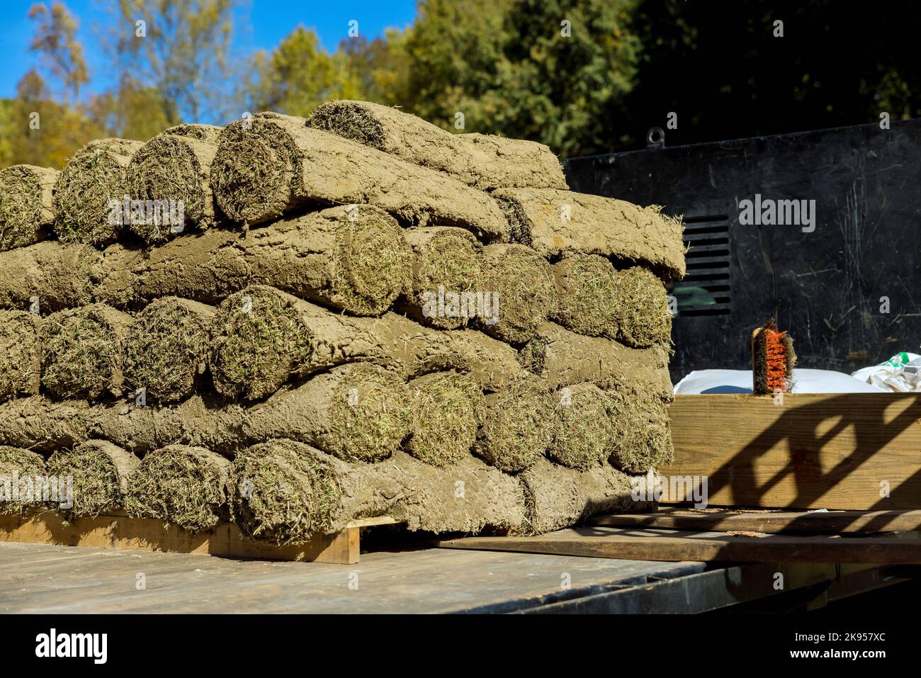 Boom truck unloading green grass turf rolls in rolls that is on pallets ...
