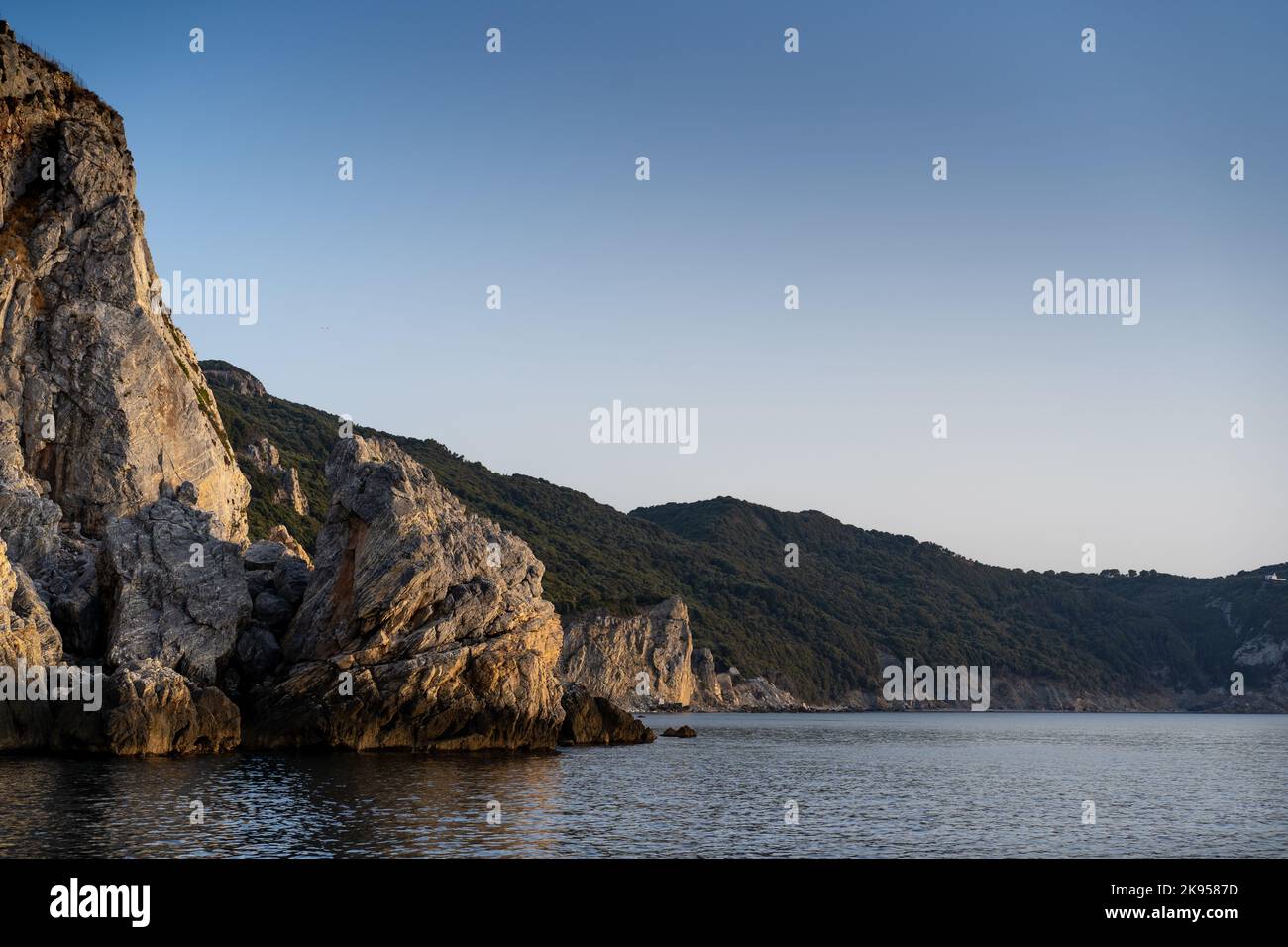 A breathtaking shot of the calm sea and rocky shore during sunset ...