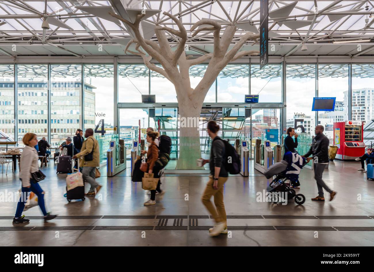 Travelers walking past a tree-shape pillar in the concourse of the SNCF ...