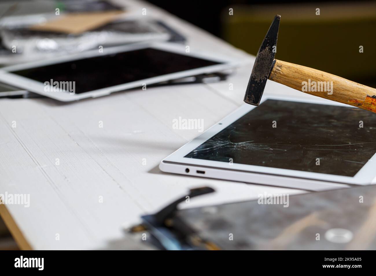 The hammer hits the broken touchscreen tablet, suggesting that it is ...