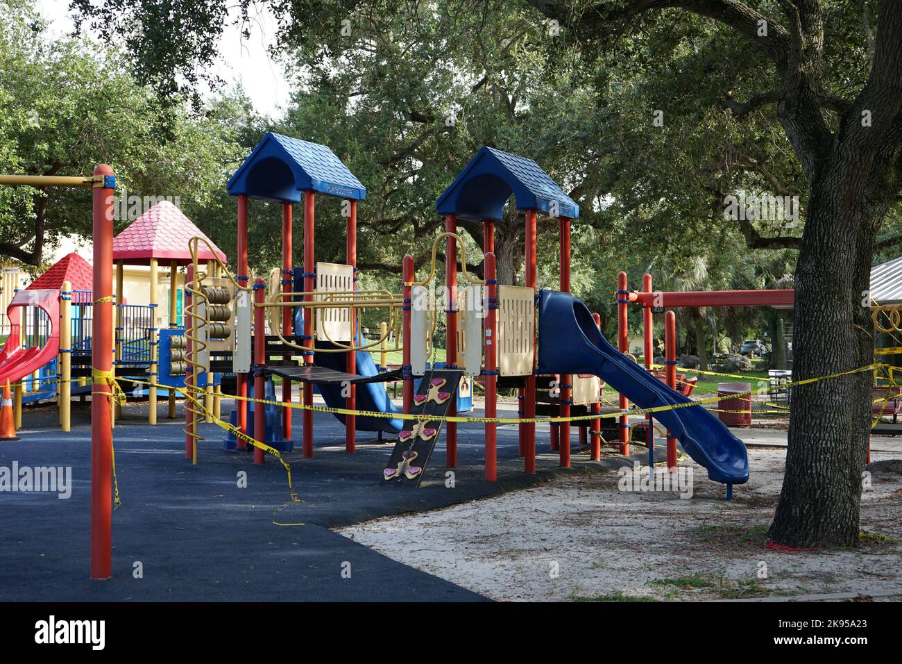 A playground in the park with slides closed with a yellow warning sign ...