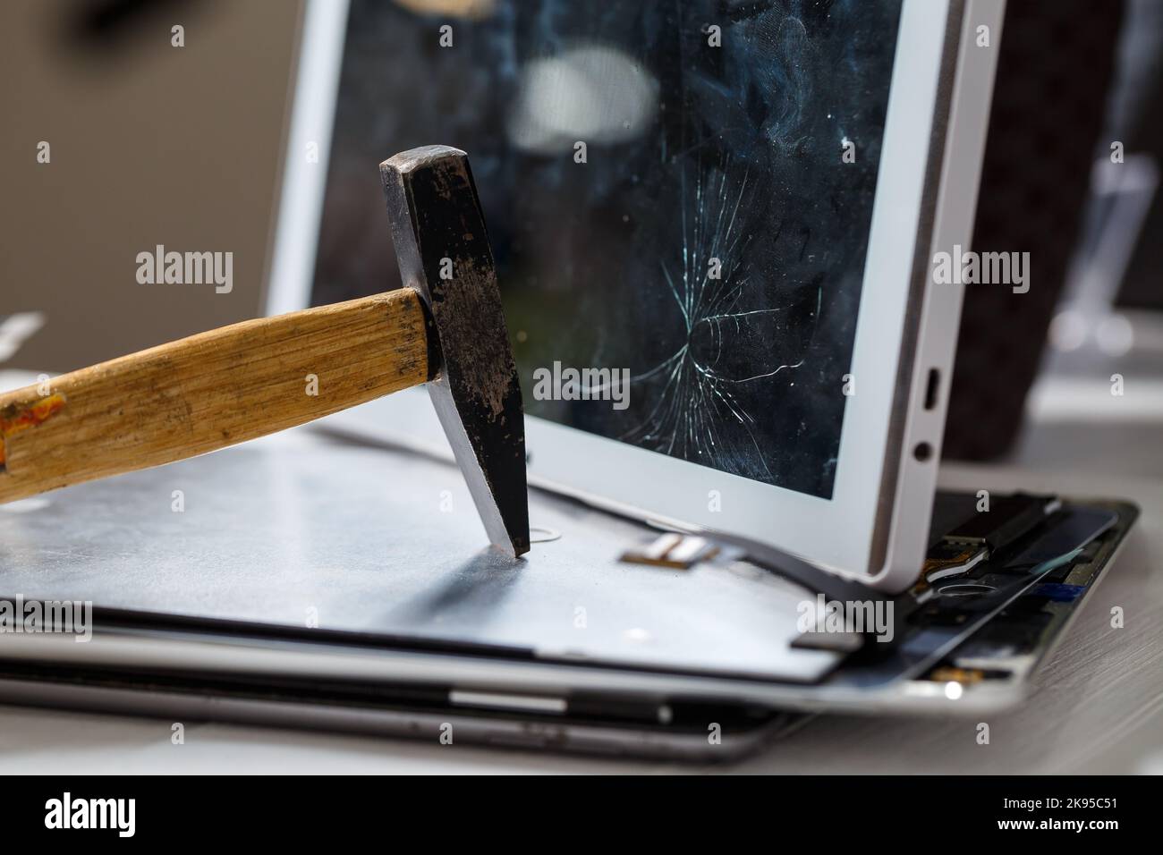 The hammer hits the broken touchscreen tablet, suggesting that it is ...