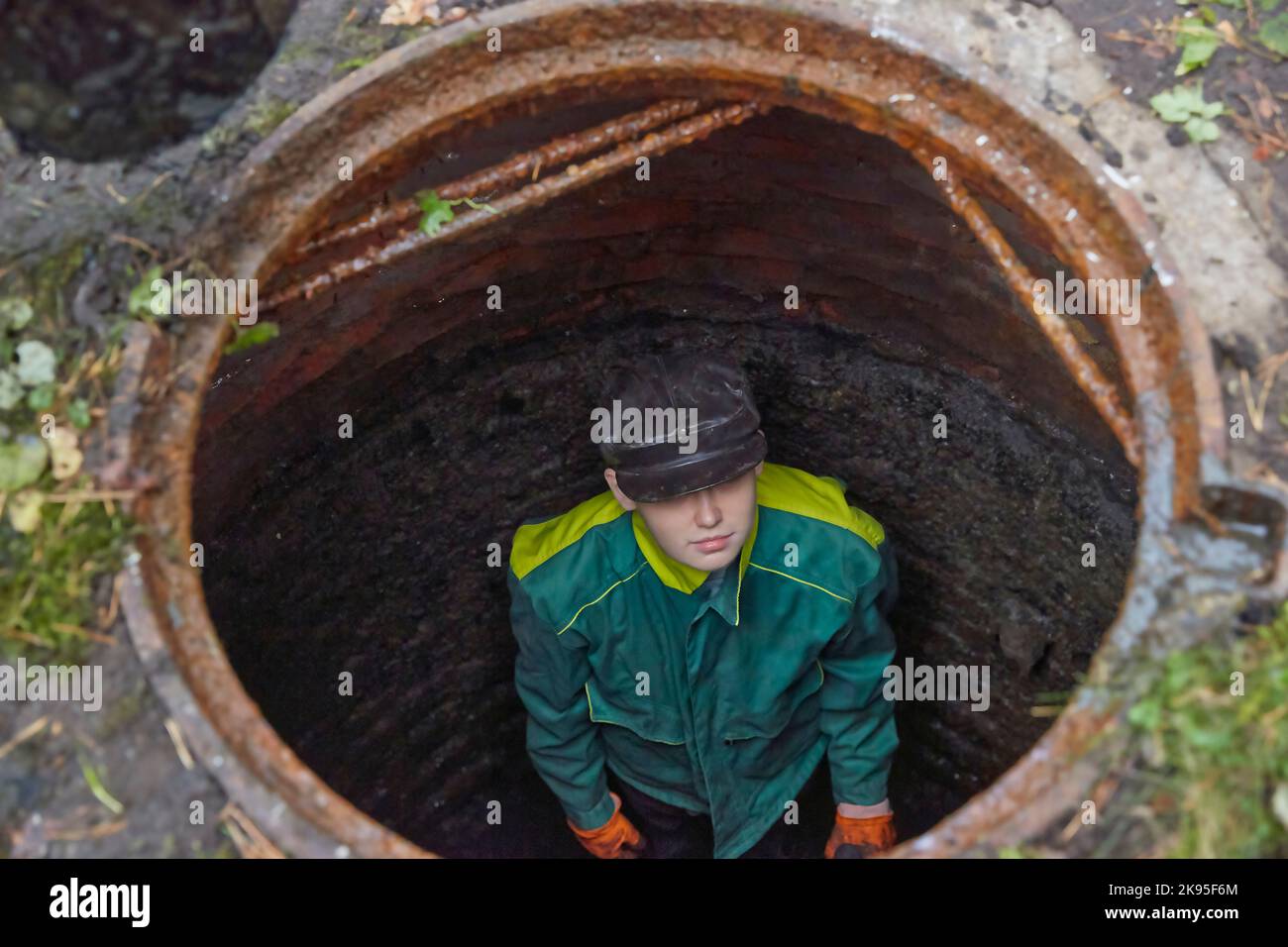 man in the drain pit. Underground utilities Stock Photo - Alamy