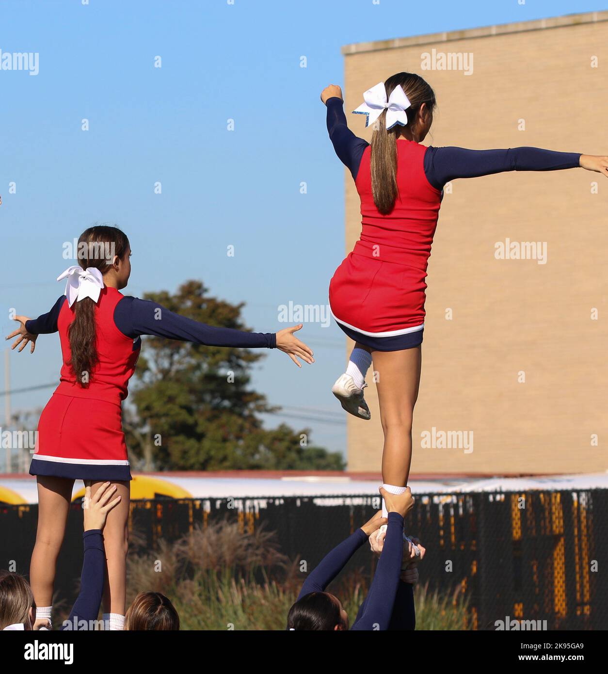 Rear View Of High School Cheerleaders Beign Held In The Air By Their Teammates Practicing Their