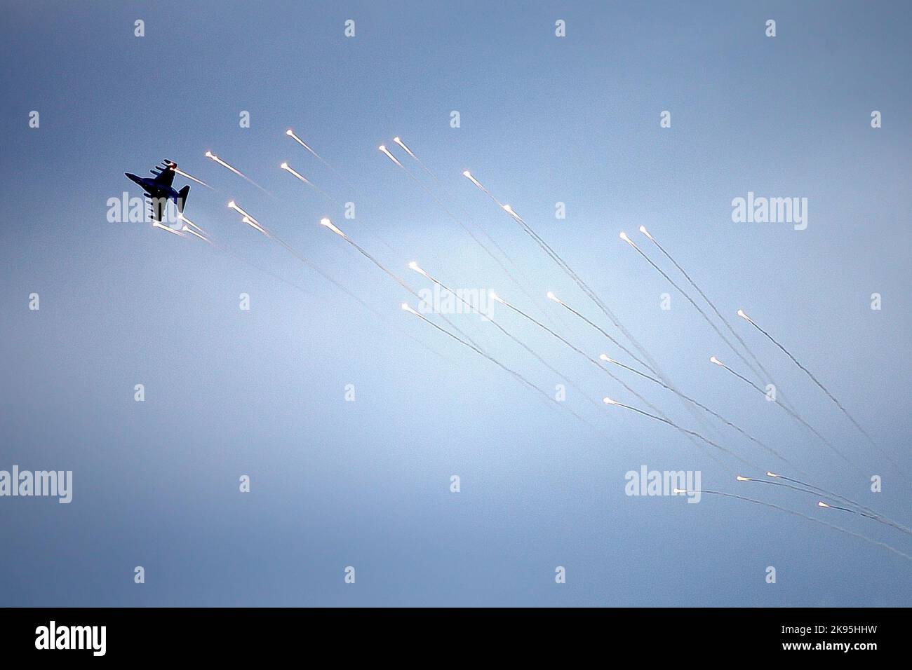 A military aircraft with combat missiles releases heat traps while ...