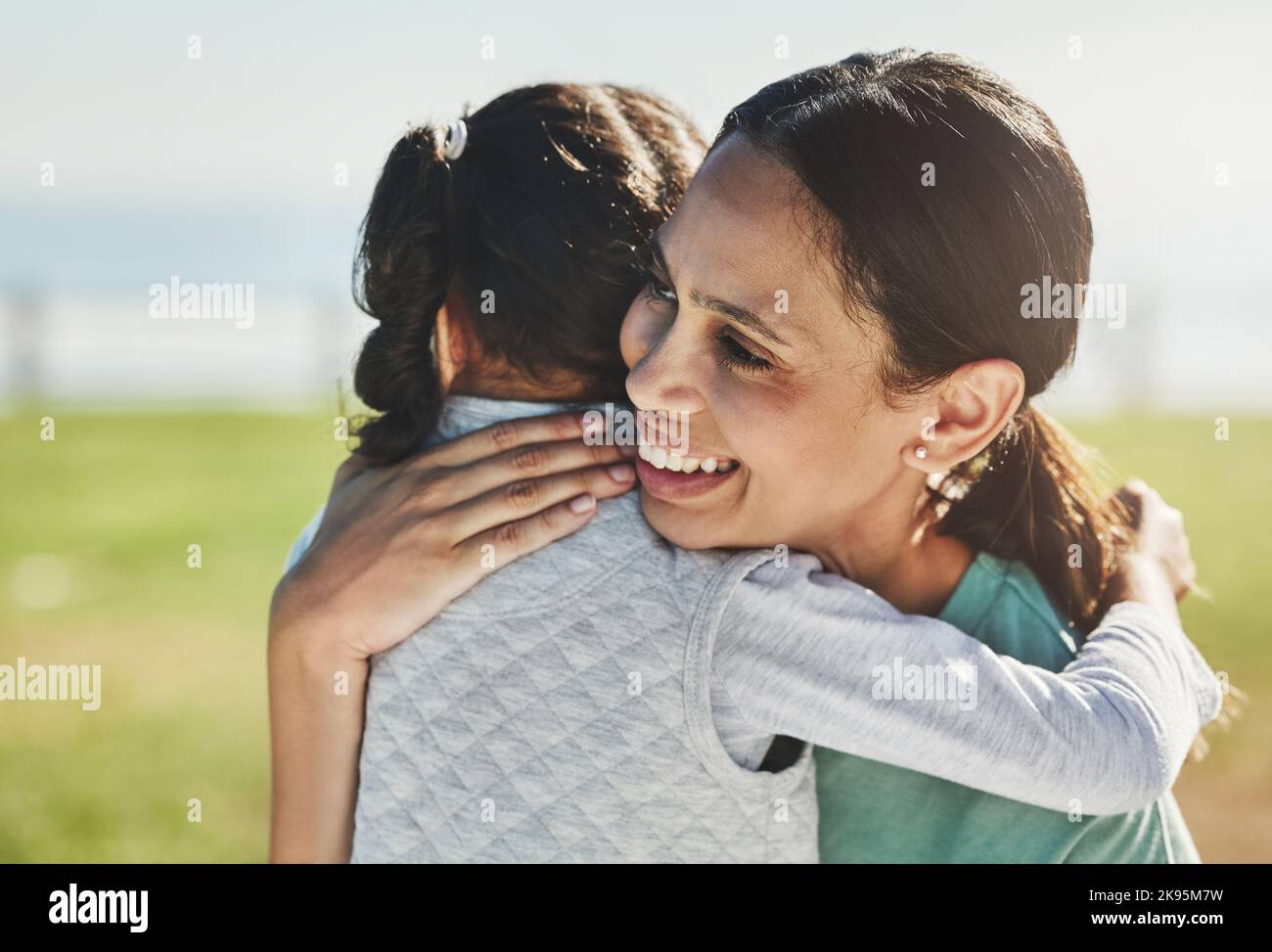 Happy, girl and kid hug mom at park for mothers day, love and relax ...