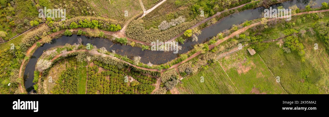 A panoramic drone view of a small river bend with a green riverbanks ...