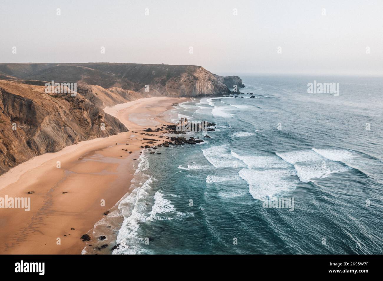 A beautiful view of a sandy beach with a cliff during sunrise Stock ...