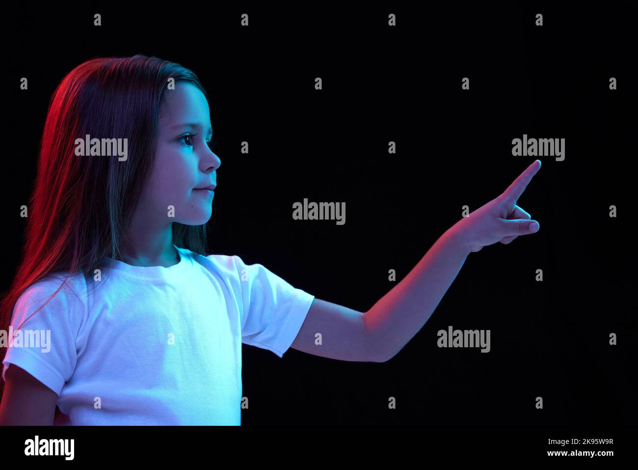 Pointing. Charming little girl, kid in white t-shirt expressing ...