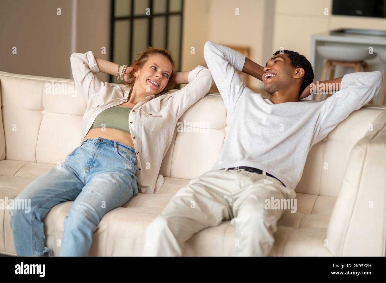 Young people lying on the sofa and looking relaxed Stock Photo - Alamy
