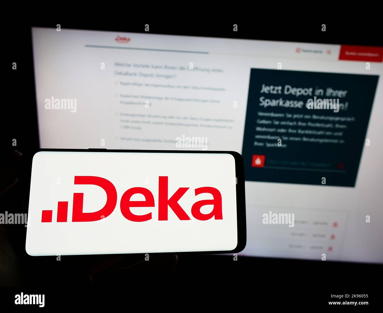 Person holding smartphone with logo of DekaBank Deutsche Girozentrale ...