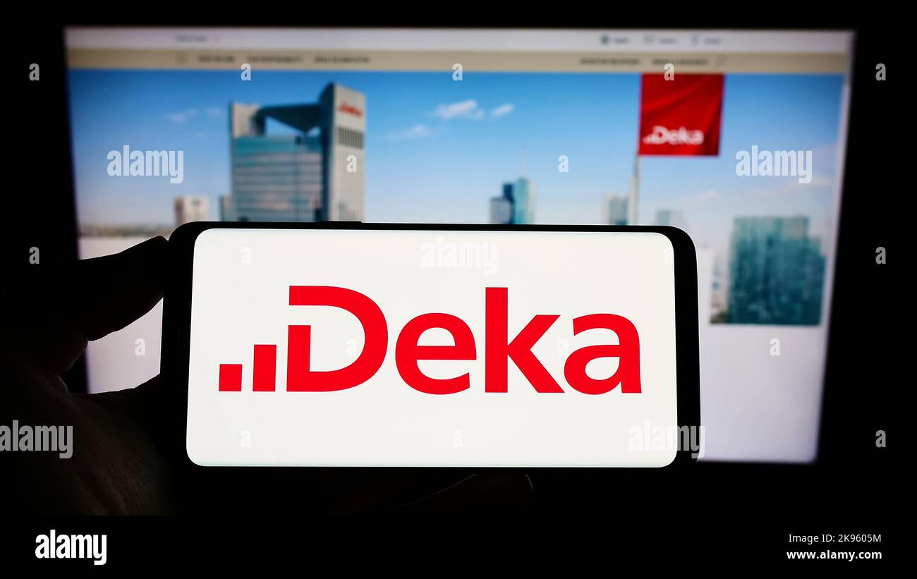 Person holding mobile phone with logo of DekaBank Deutsche Girozentrale ...