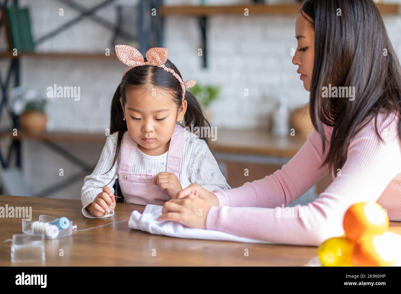 Female and her child involved in hand sewing Stock Photo - Alamy