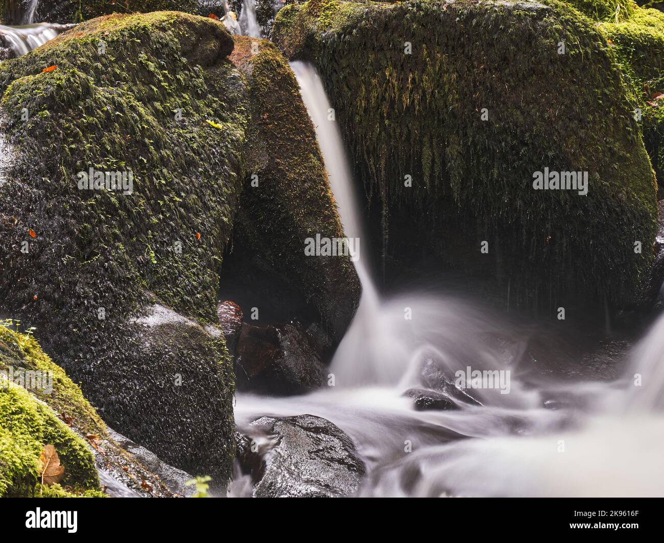 Long exposure of small water fall and moss covered boulders. Part of ...