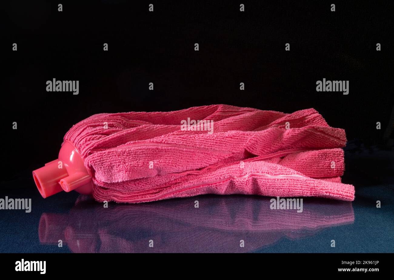 A pink microfiber mop head on a glass table. Household items with ...