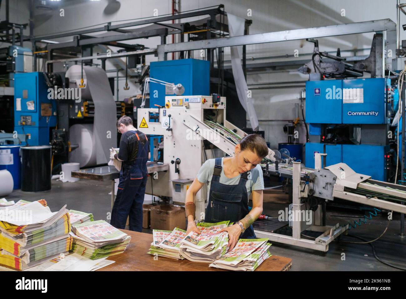 Woman stacking magazines on print shop Stock Photo - Alamy