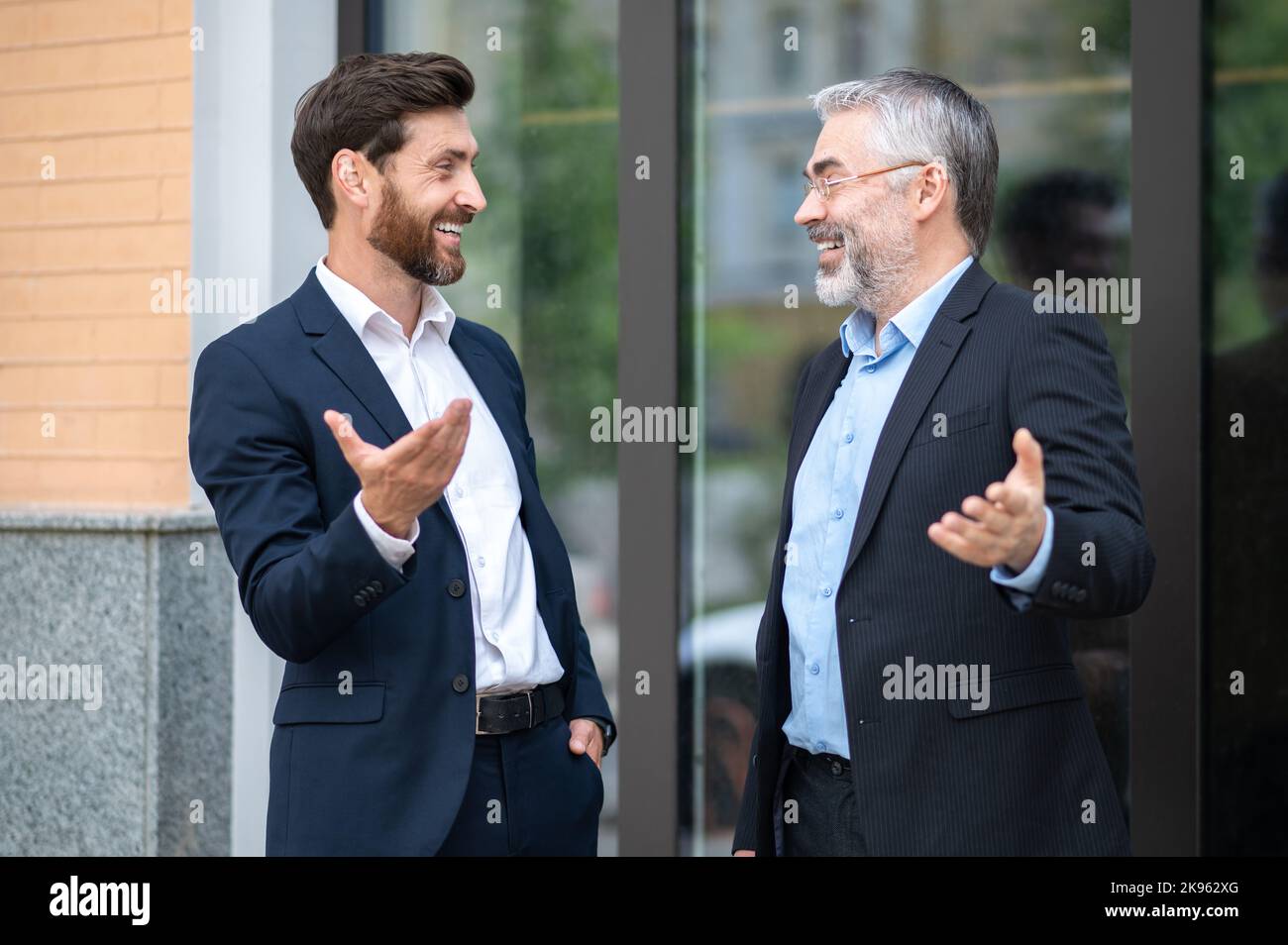 Two elegant men talking and looking interested Stock Photo - Alamy