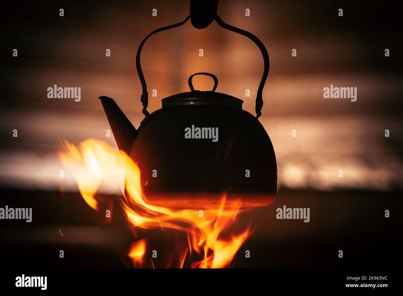 The view of a retro teapot hung over fire flames in a room Stock Photo ...
