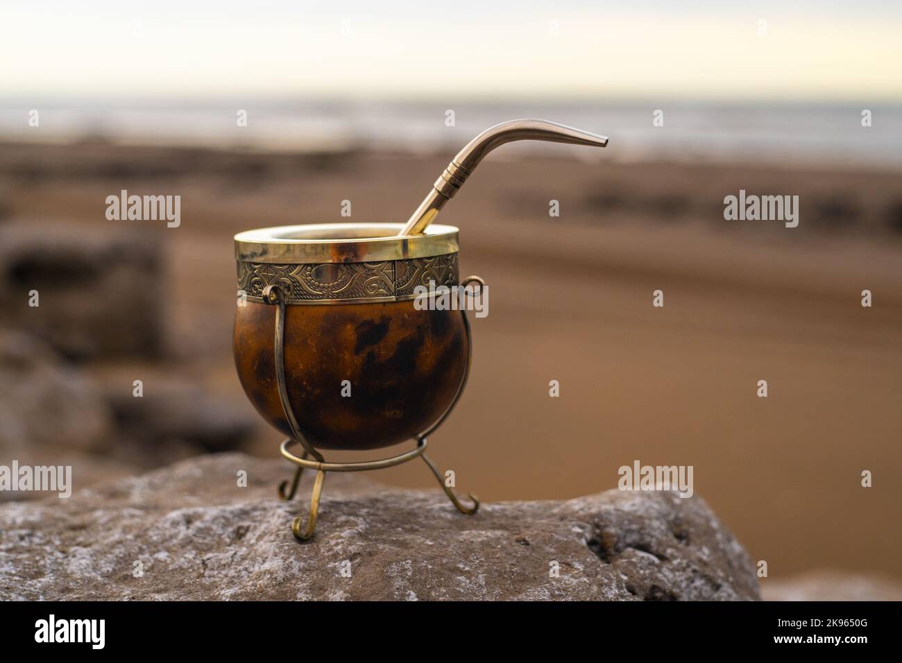 A closeup of an Argentinian yerba mate cup in golden and brown colors ...