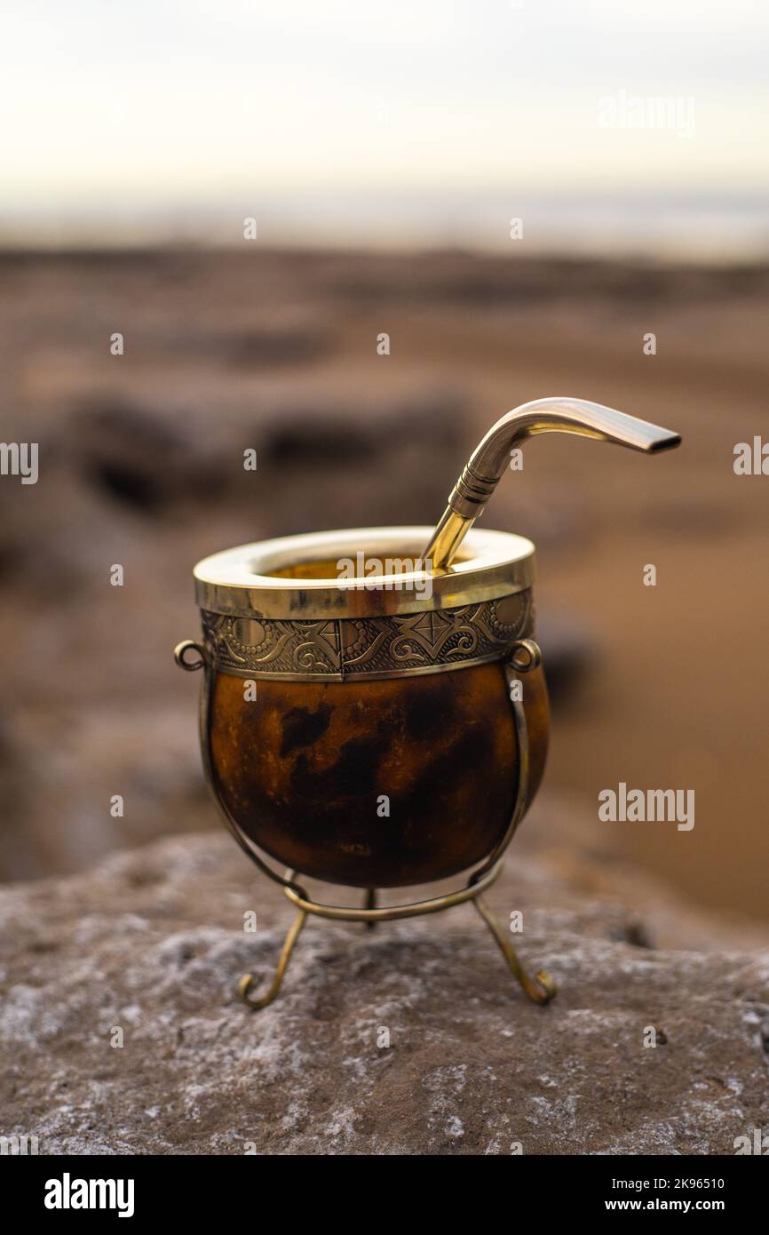 A vertical shot of an Argentinian yerba mate cup in golden and brown ...