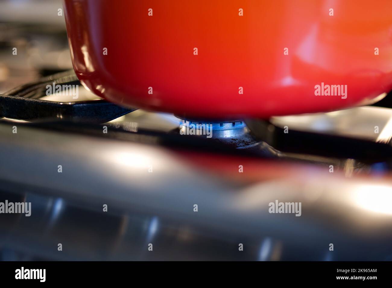 Focus on natural gas burner with blue flames under pot on cooking stove ...