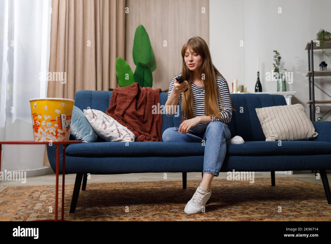 Pretty young woman watching TV programs while sitting on comfortable ...