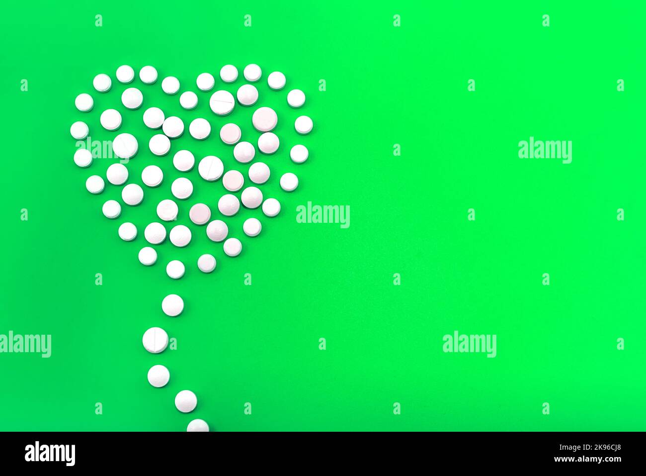 Heart-shaped white medical pills on a green background. Tablet. Health ...