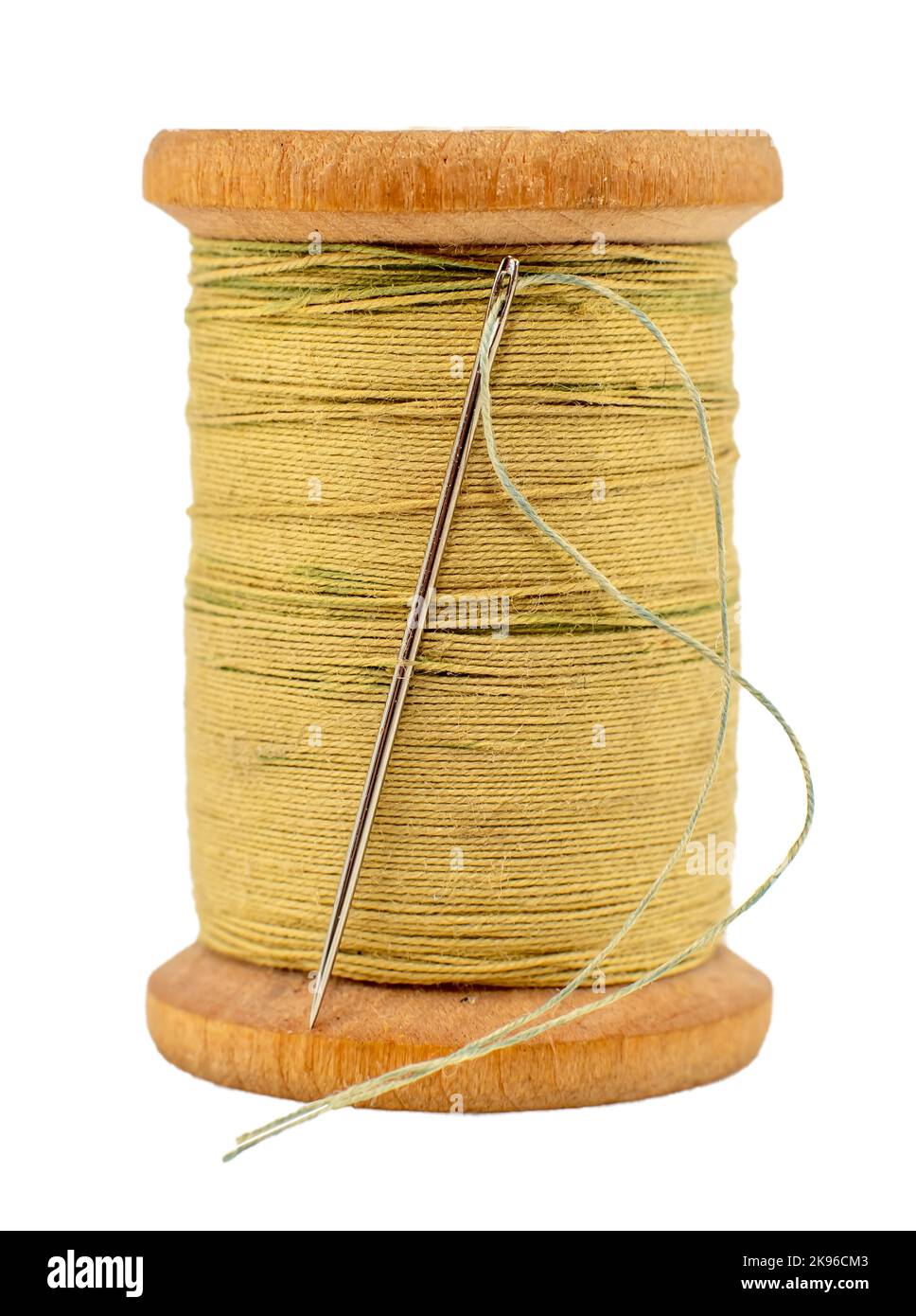 An old wooden spool of thread and a needle on a white background close ...