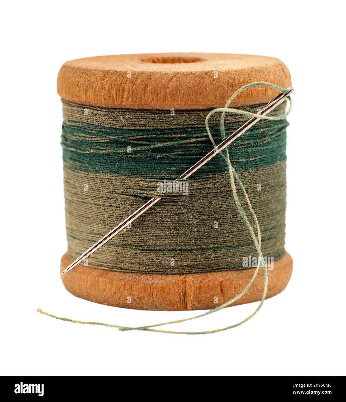 An old wooden spool of thread and a needle on a white background close ...