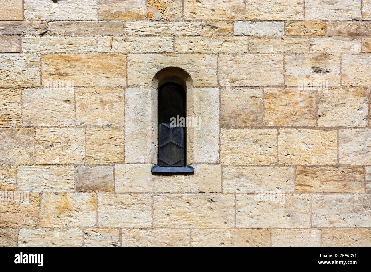 Narrow window, closed with iron shutters, in a stone wall of red and ...