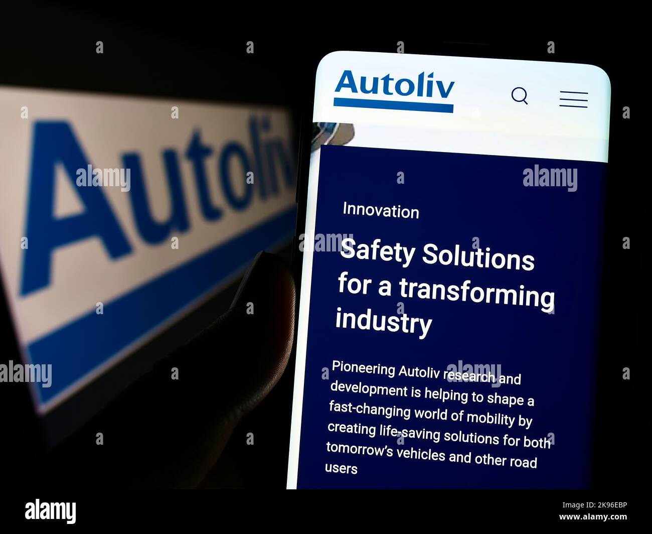 Person holding cellphone with webpage of automotive supply company ...
