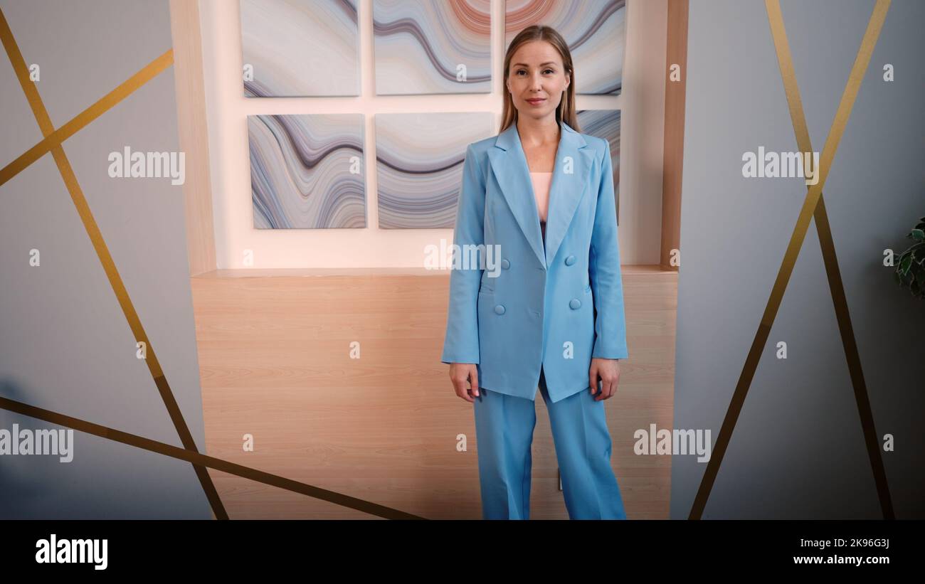 A portrait of a businesswoman in a formal outfit posing in front of a ...