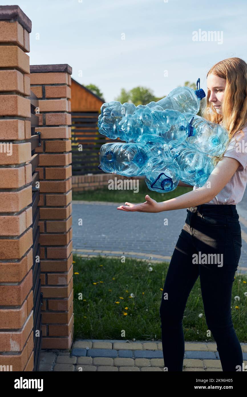Young woman throwing out empty used plastic water bottles into trash ...