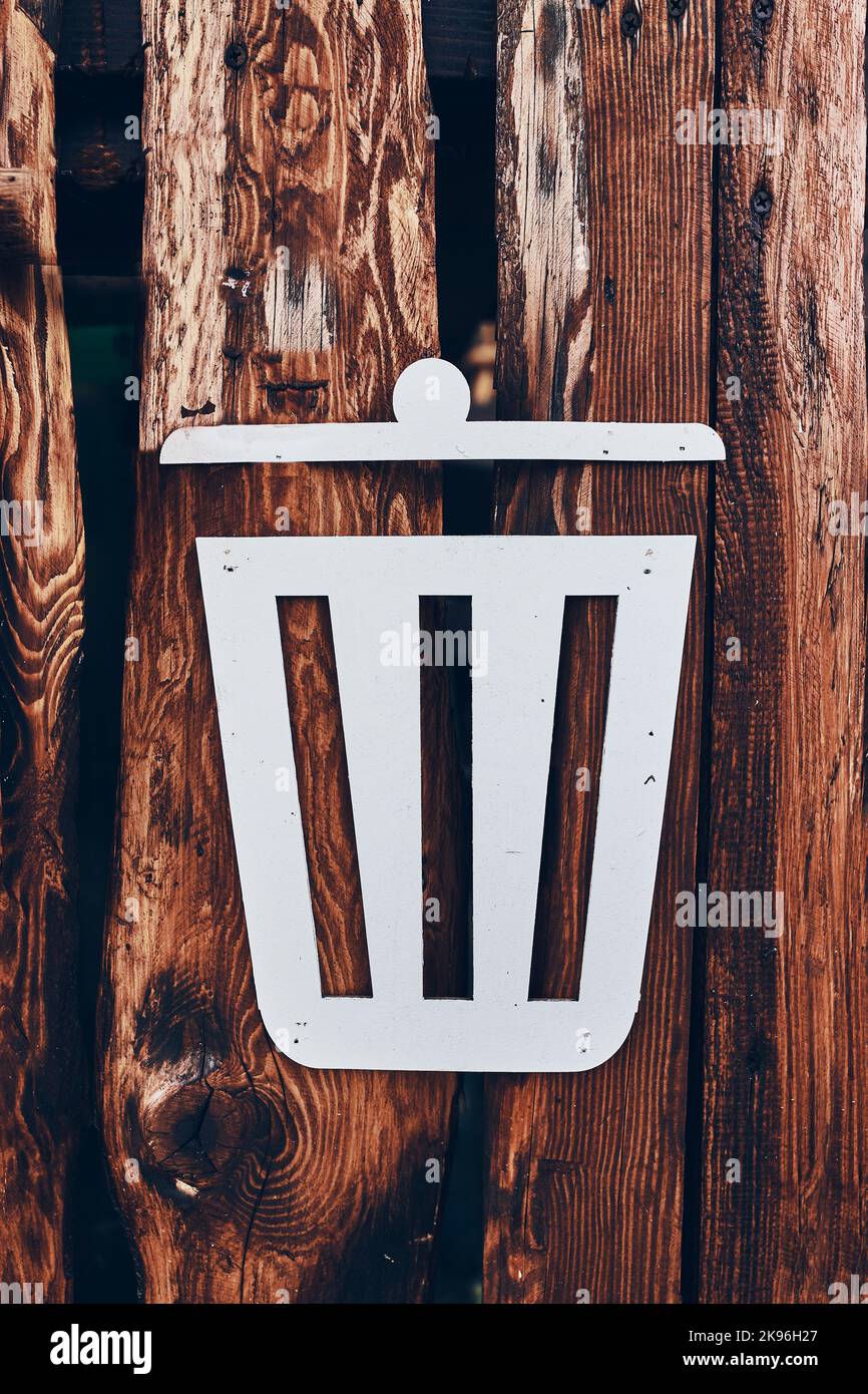 Trash bin sign on wooden plank wall. White waste basket symbol on brown ...