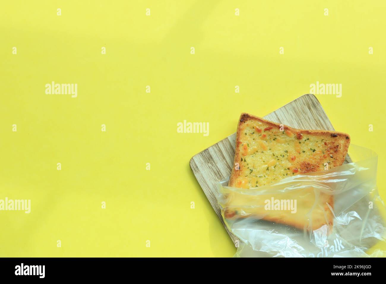 garlic bread on chopping board on yellow background Stock Photo - Alamy