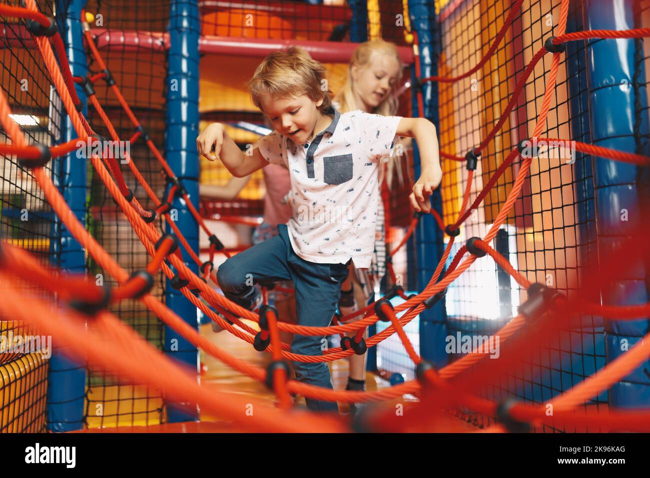 Excited kids playing together on net ropes. Happy group of siblings ...