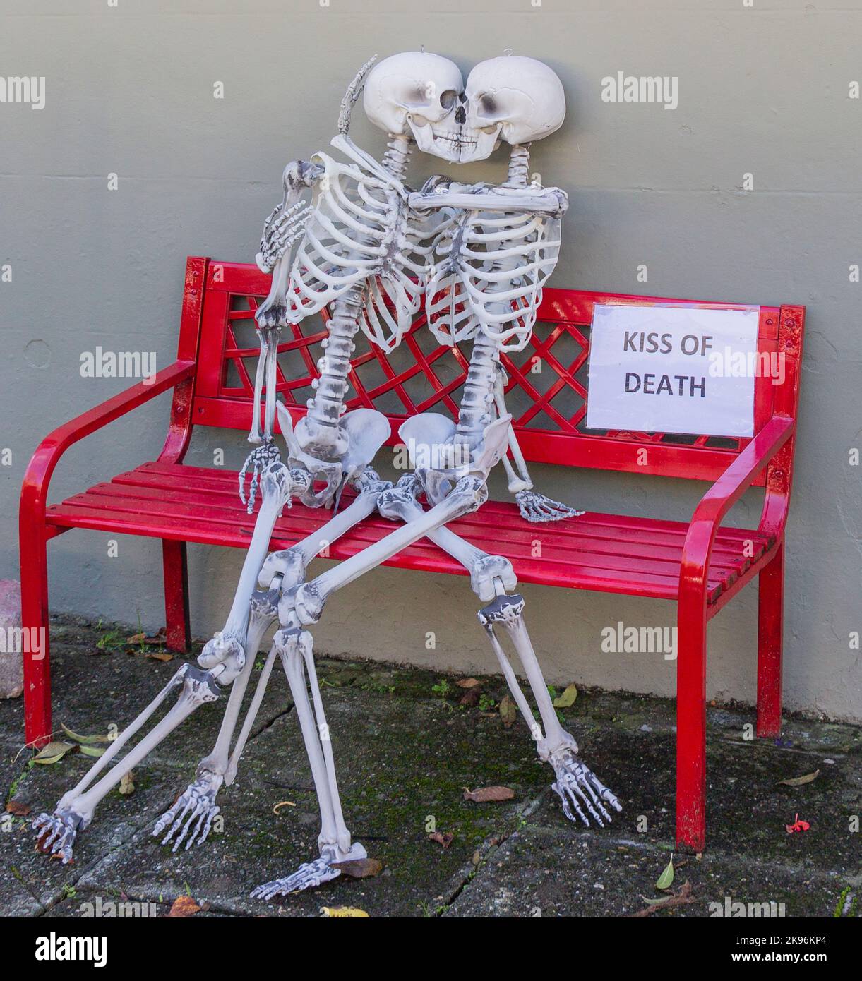 Halloween Skeletons on a red bench kissing Stock Photo - Alamy