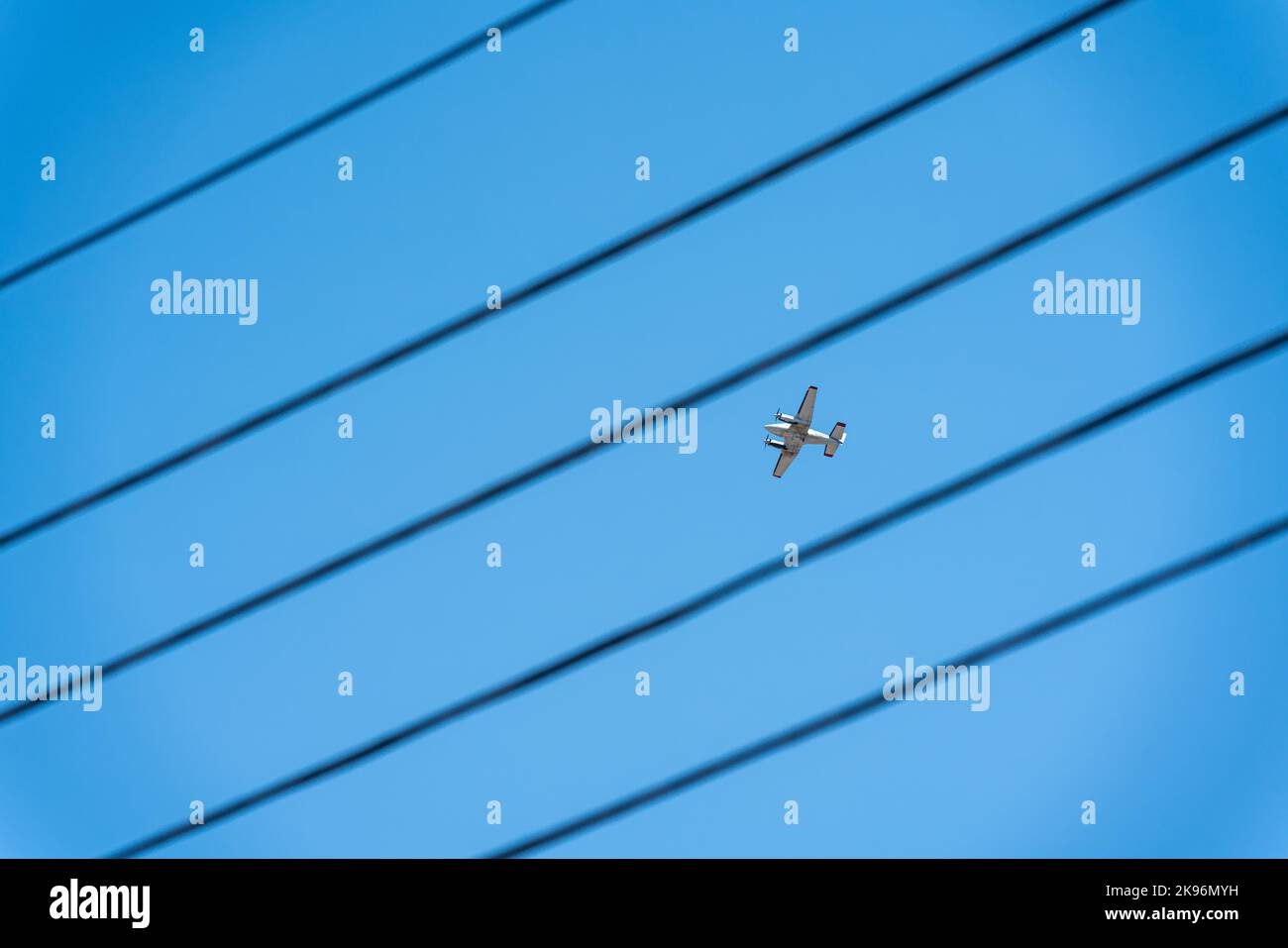 A low-angle shot of the airplane flying in the sky with power lines ...